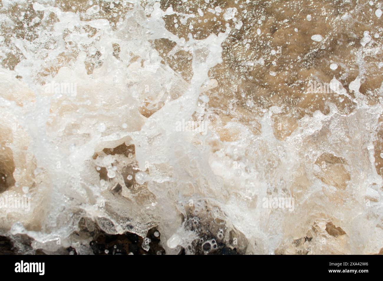 Beach water hitting the dark rocks. Preserved nature Stock Photo - Alamy