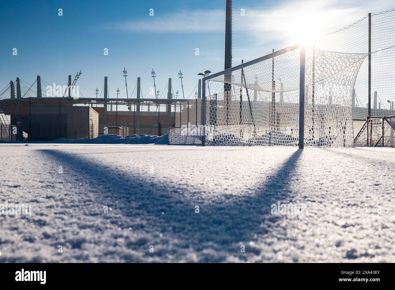 Frozen football pitch covered by snow and stadium in the background ...