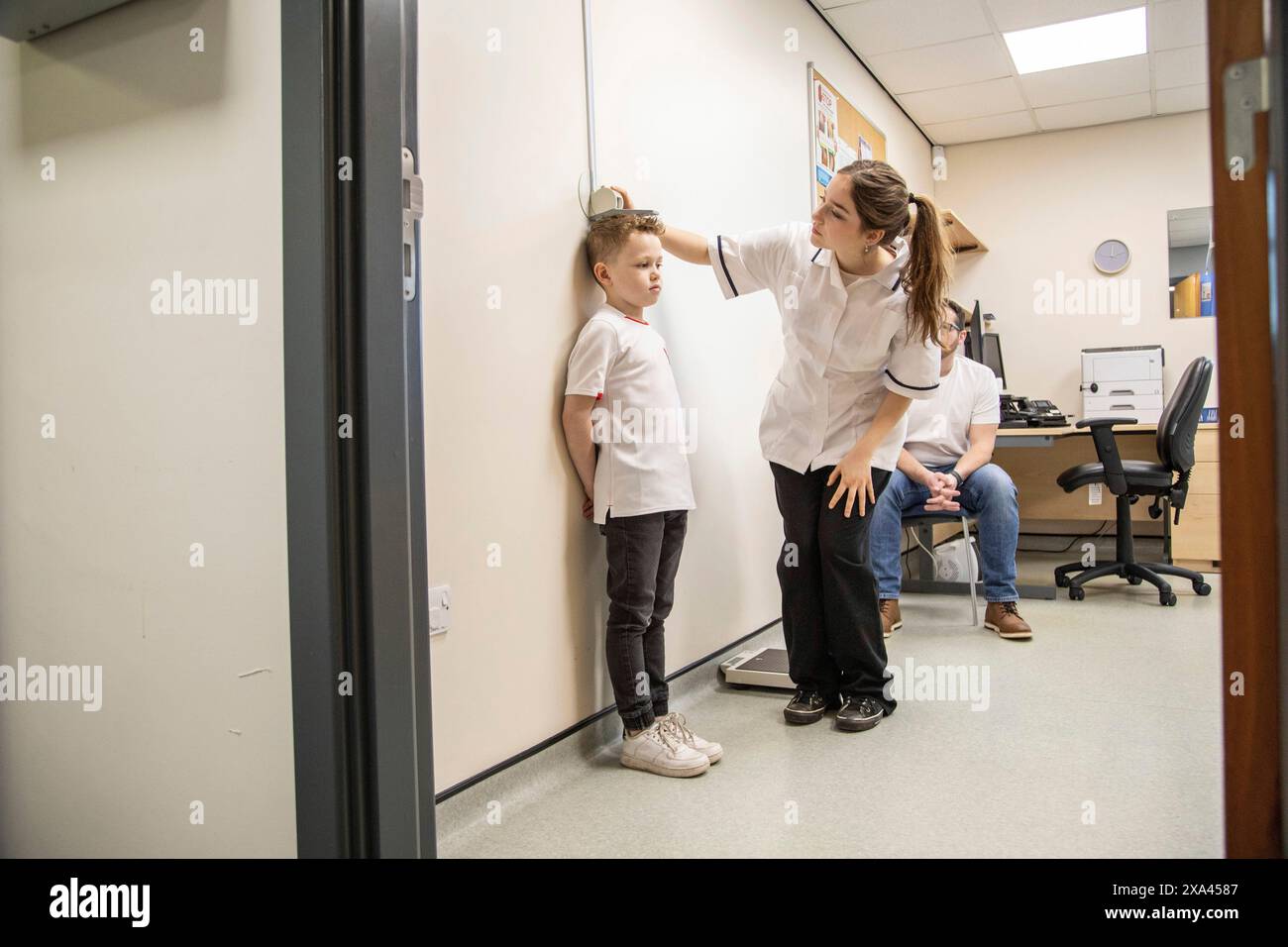 Child being measured during a medical check-up as father observes Stock ...