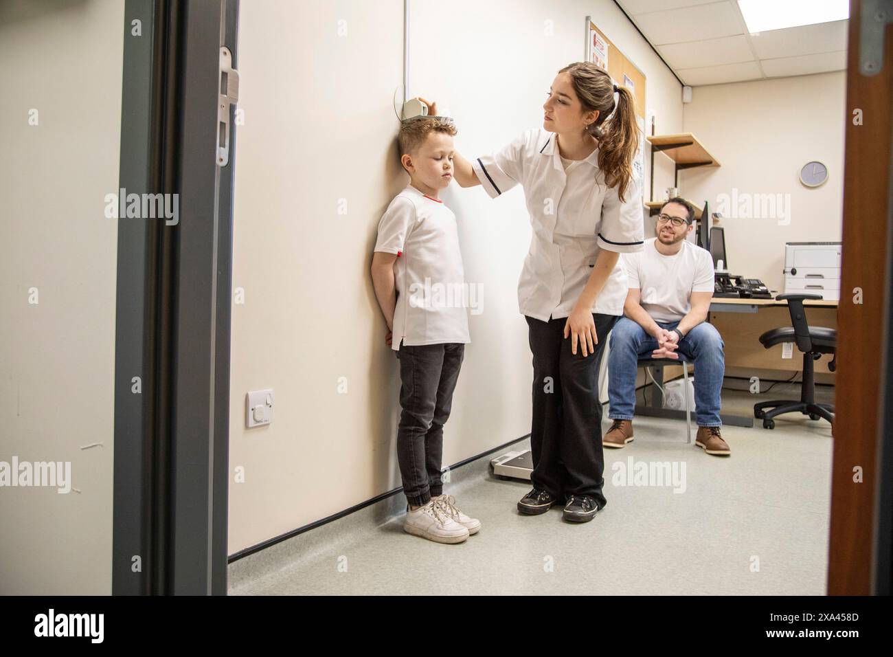 Child being measured during a medical check-up as father observes Stock ...