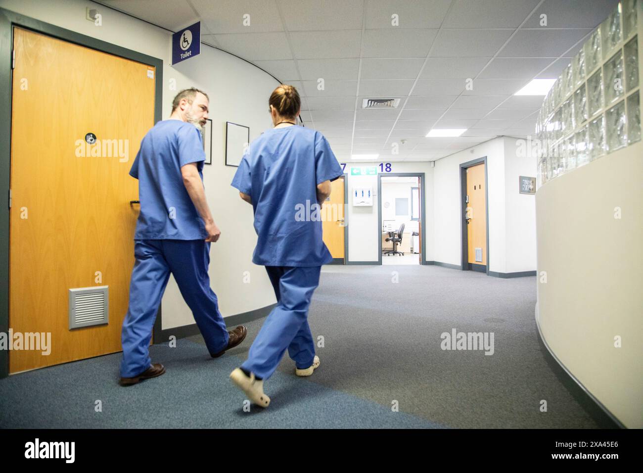 Two healthcare workers walking in a hospital corridor, medical practice ...