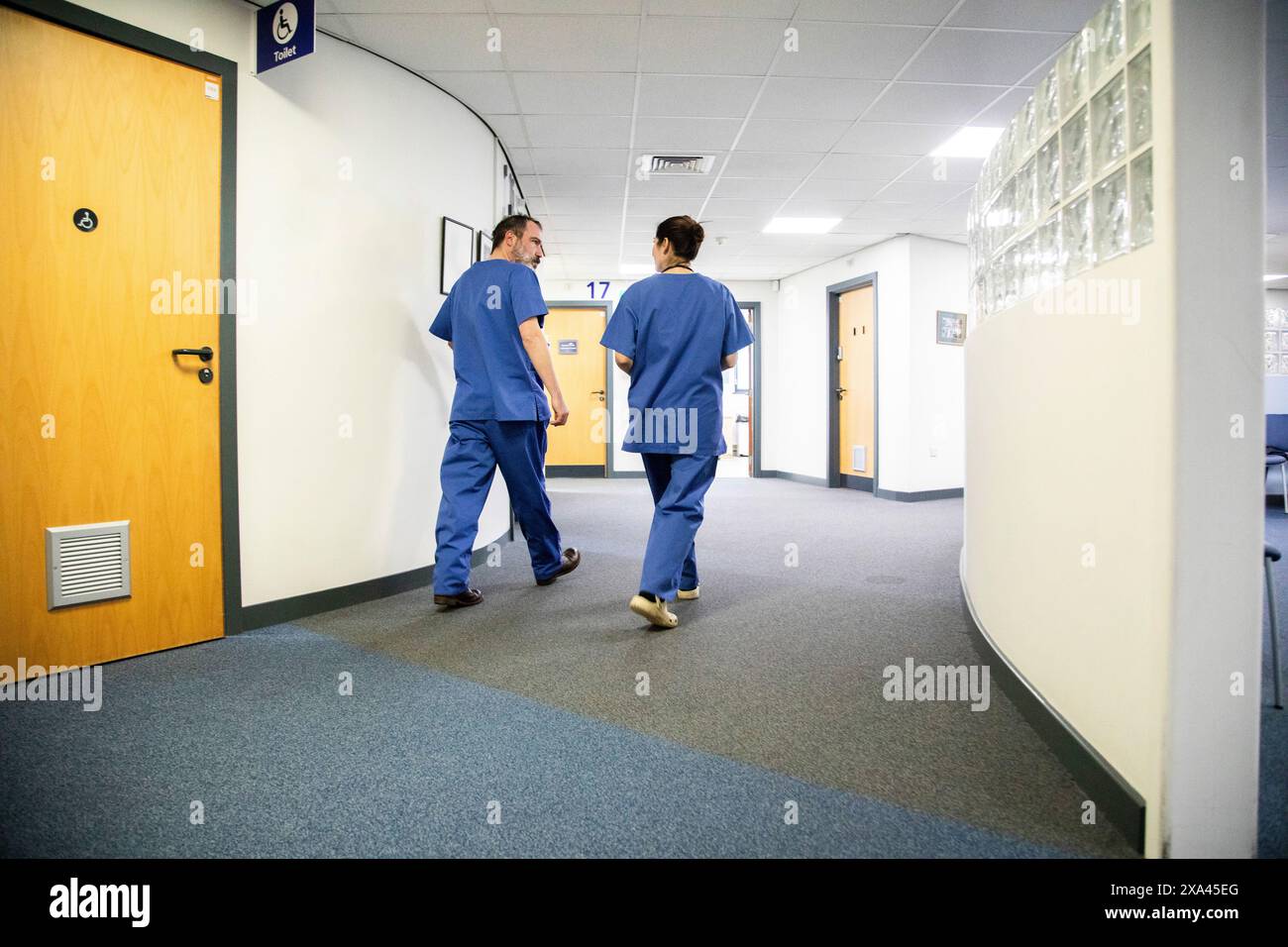 Two healthcare workers walking in a hospital corridor, medical practice ...