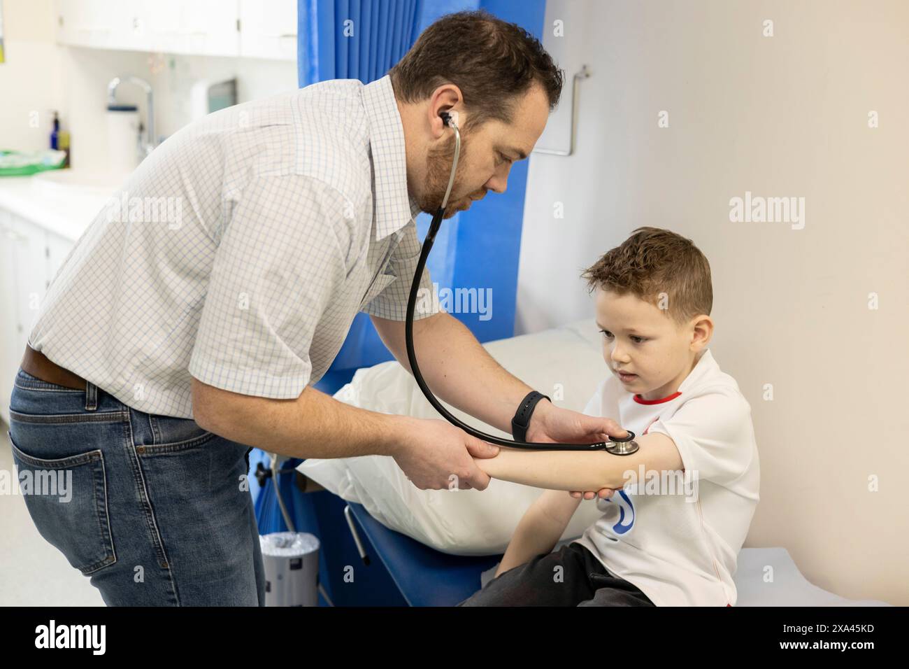 Doctor performing a checkup on a young boy Stock Photo - Alamy