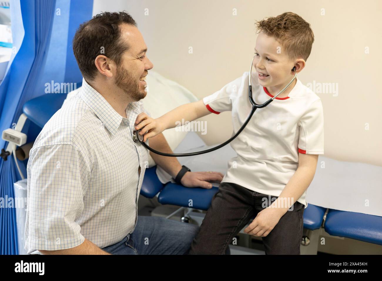 Boy using stethoscope on doctor for fun Stock Photo - Alamy