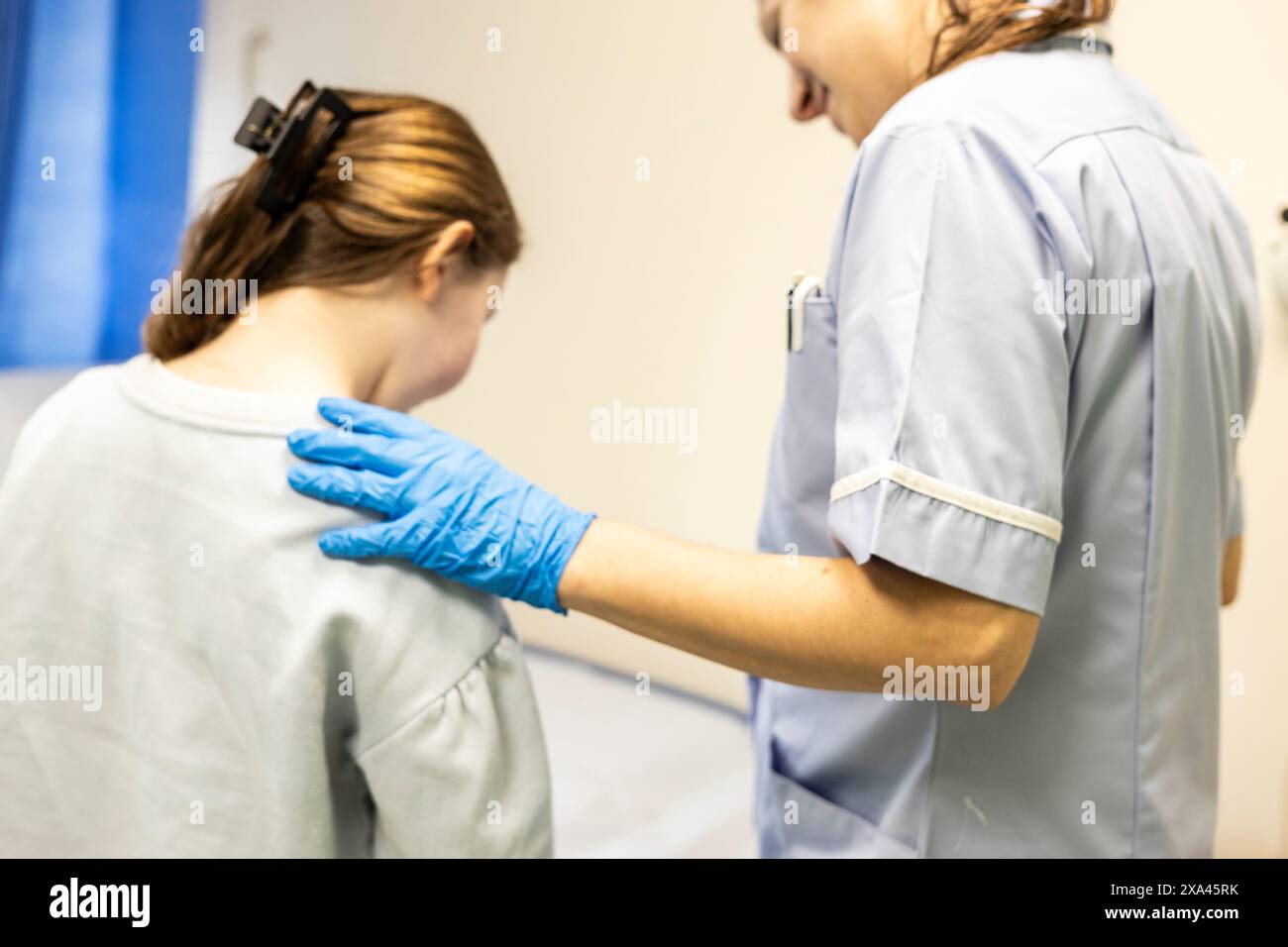 Medical professional palpating patient's back while on a scale in a ...