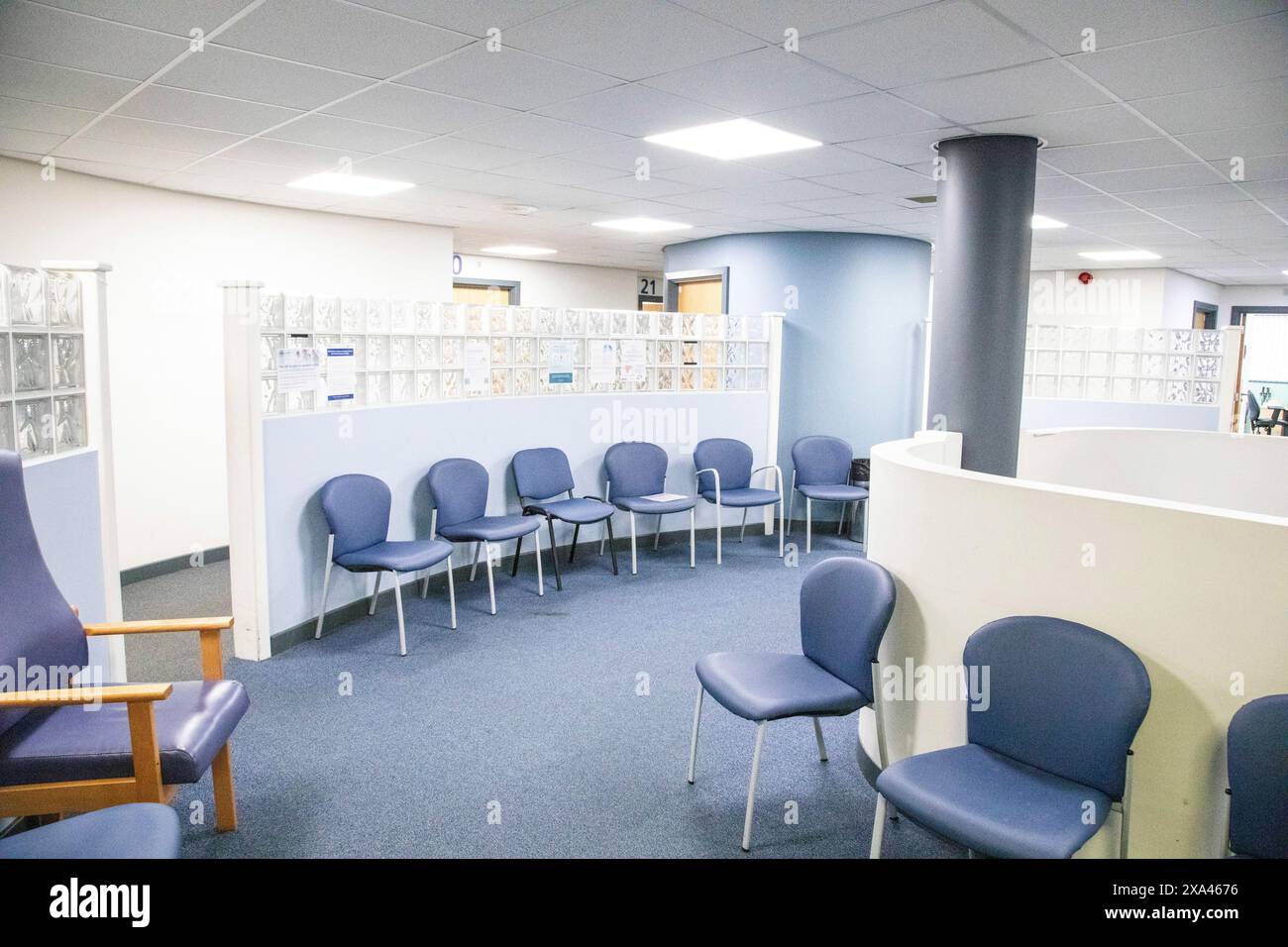 Empty waiting room with blue chairs and wall-mounted bulletin boards of ...