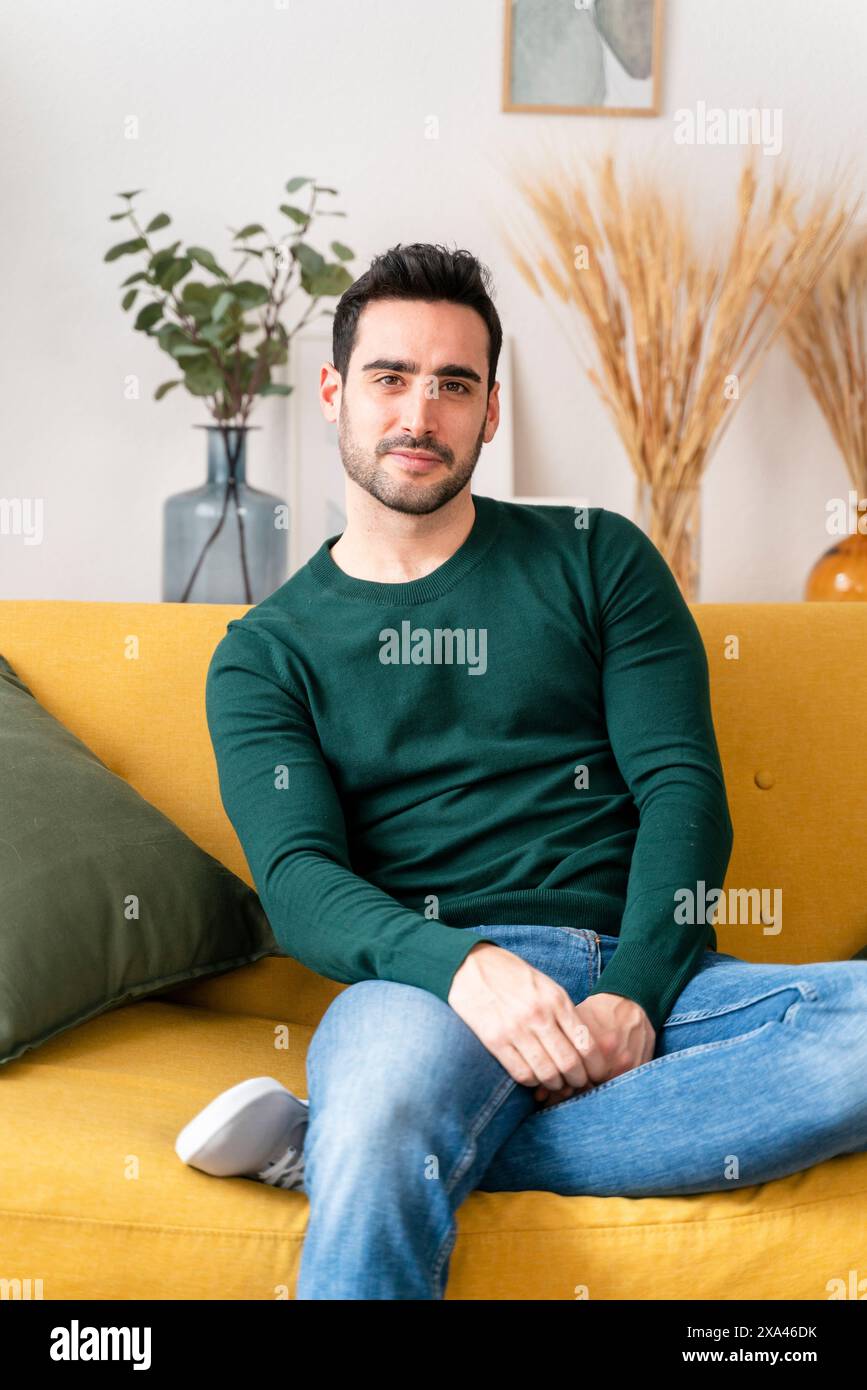 Man sitting on a yellow sofa with crossed legs Stock Photo - Alamy