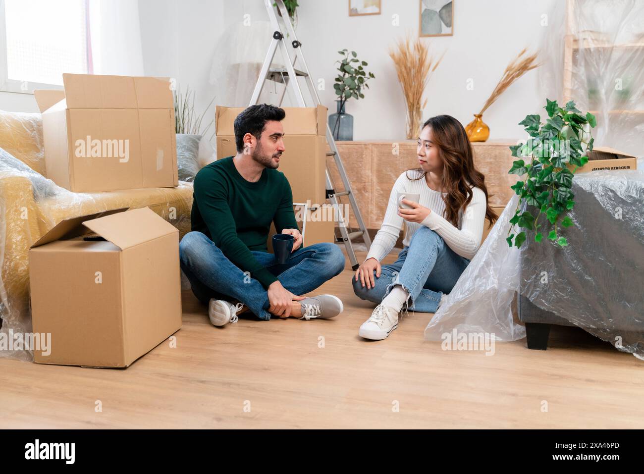 Couple sitting among moving boxes in a new home Stock Photo - Alamy