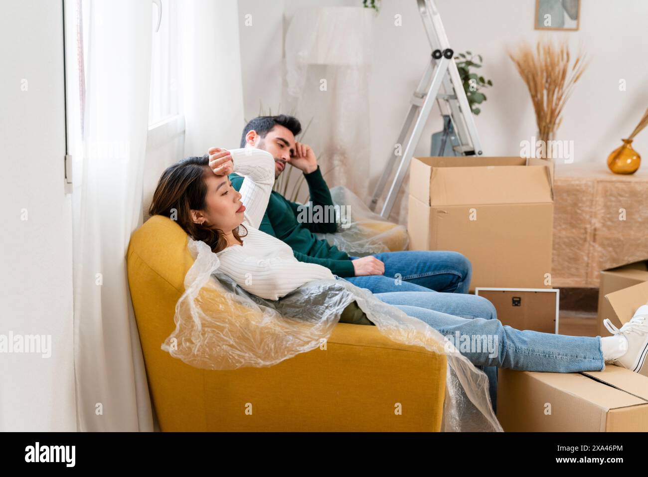 Couple resting on a couch during moving day Stock Photo - Alamy