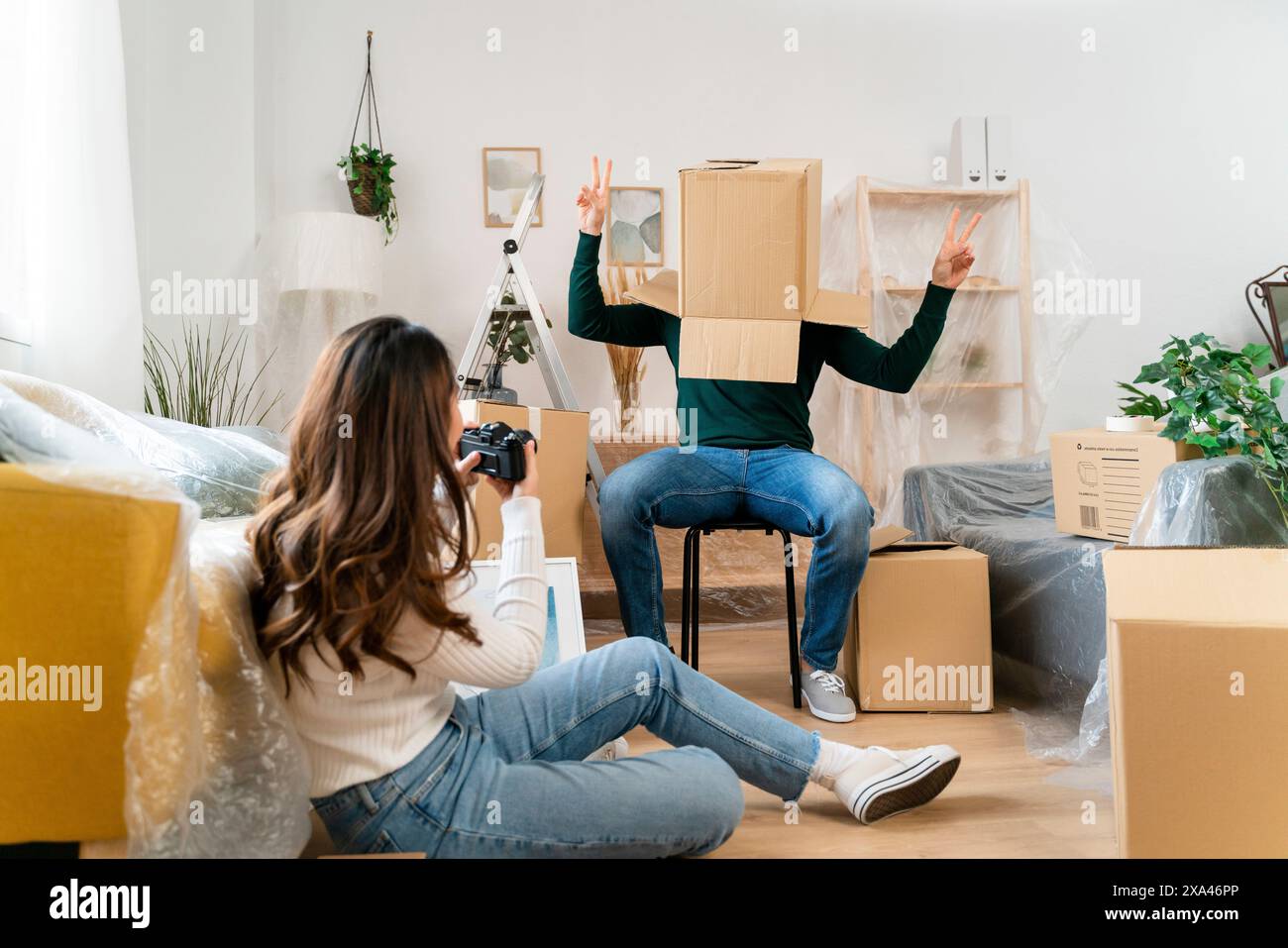 Woman photographs man with box on head in new home Stock Photo - Alamy