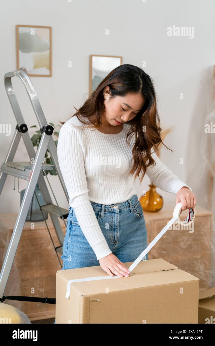 Woman measuring a cardboard box with a tape Stock Photo - Alamy