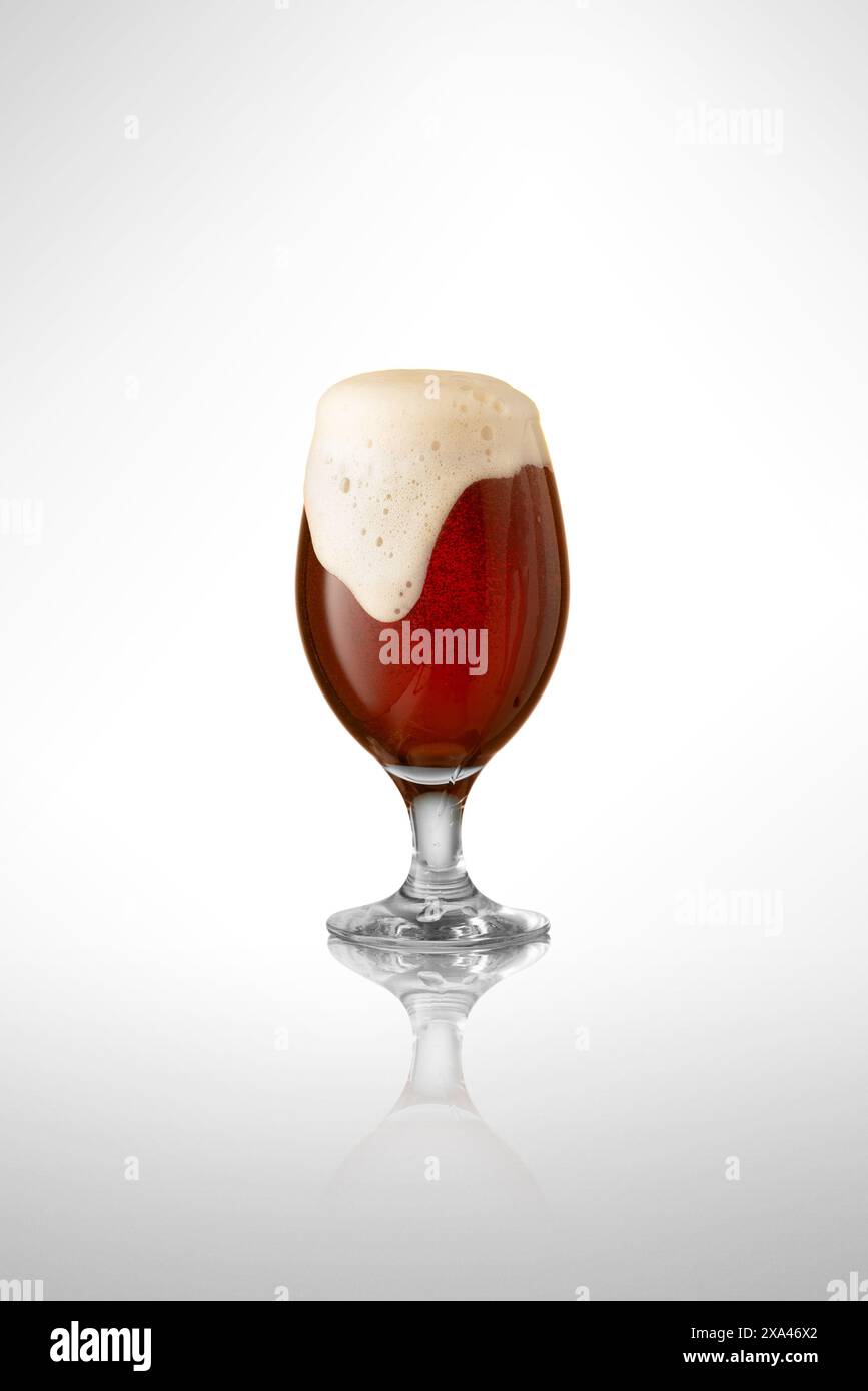 Photo of glass goblet brimming with dark craft beer, topped with thick ...