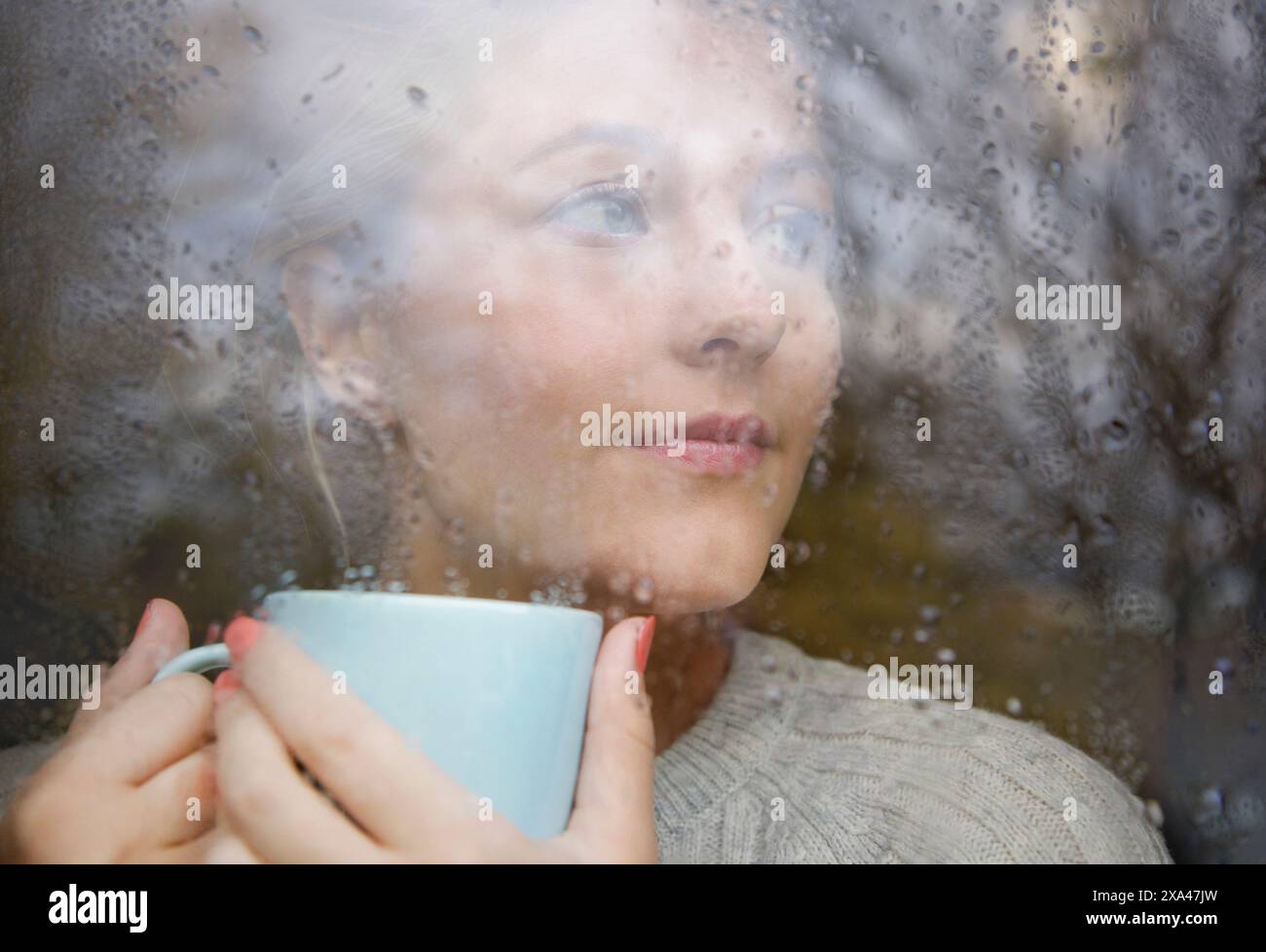 Woman Holding Drinking Cup behind Rainy Window Stock Photo - Alamy