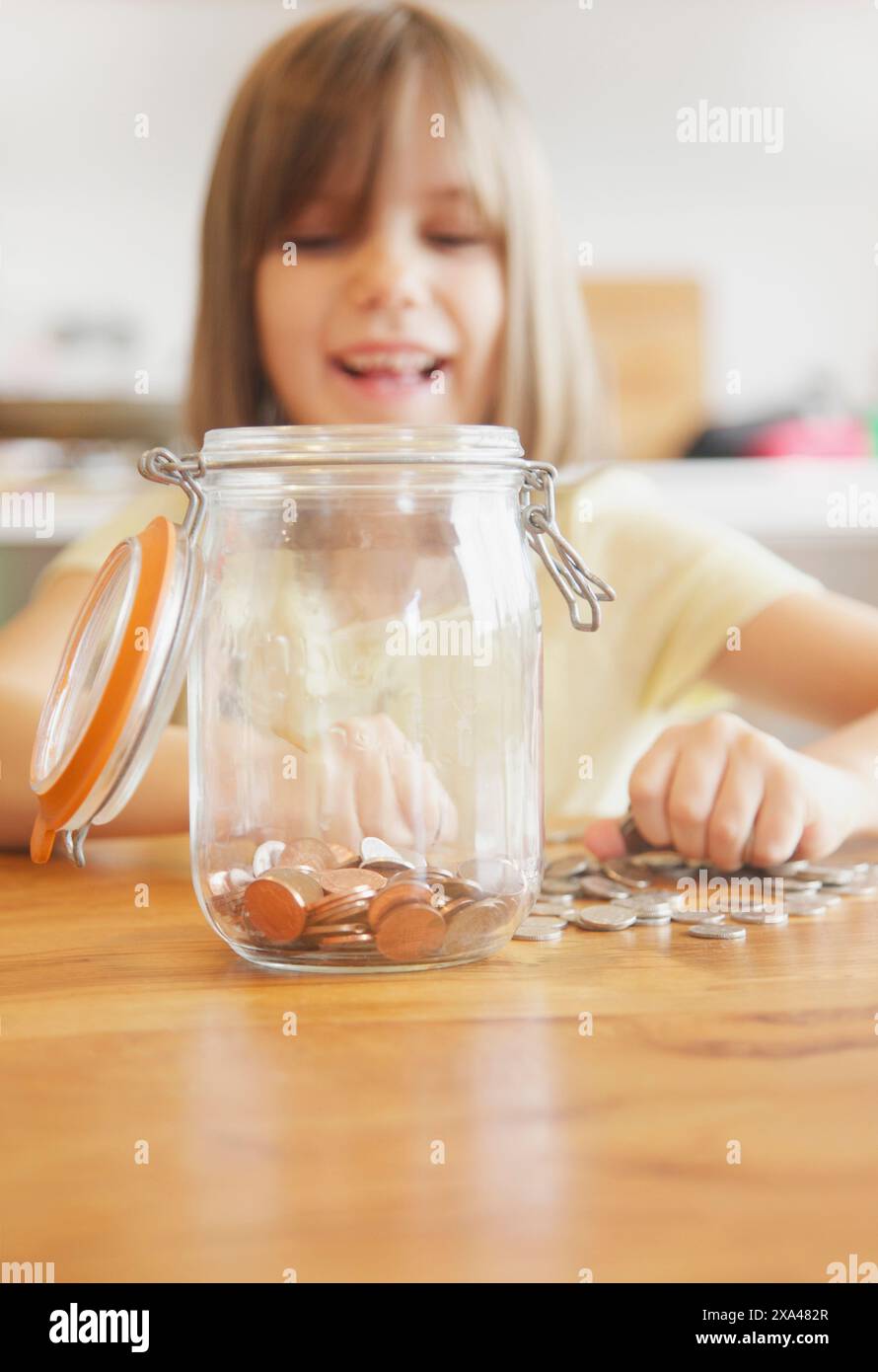Kid putting money in jar hi-res stock photography and images - Alamy