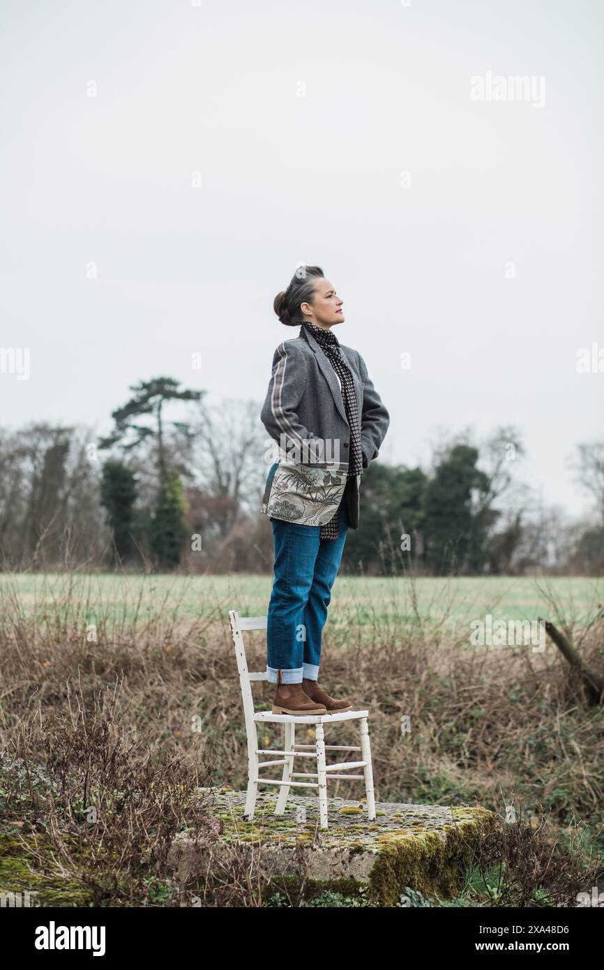 Woman Standing on Chair in a Field Stock Photo - Alamy