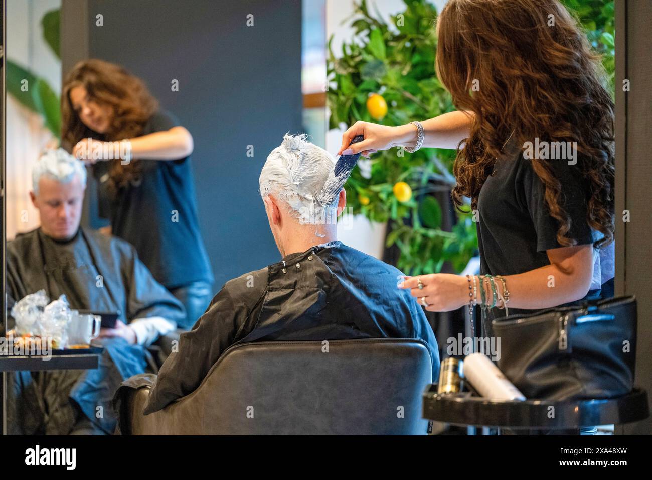 Hairstylist applying color to client's hair in salon Stock Photo - Alamy