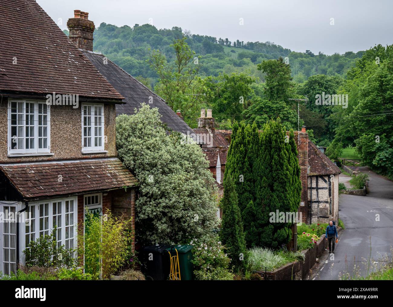 Street scene in a rural setting with old houses and a hiker on the road ...