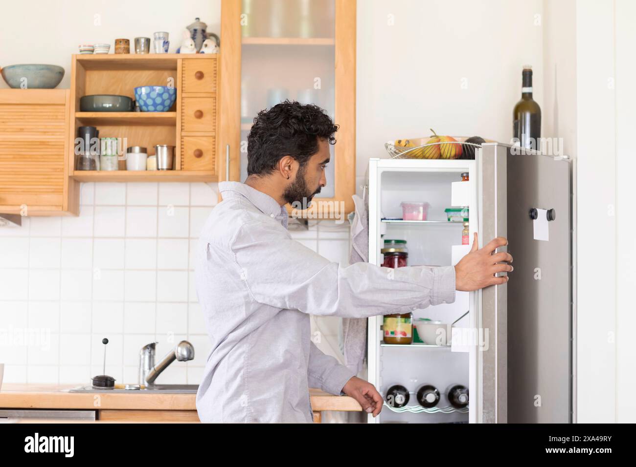 Man opening refrigerator full various food items well lit hi-res stock ...