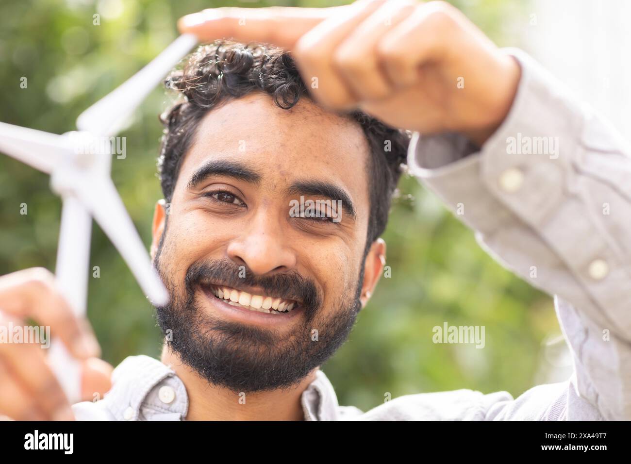 A smiling man with a beard holding a miniature wind turbine Stock Photo ...