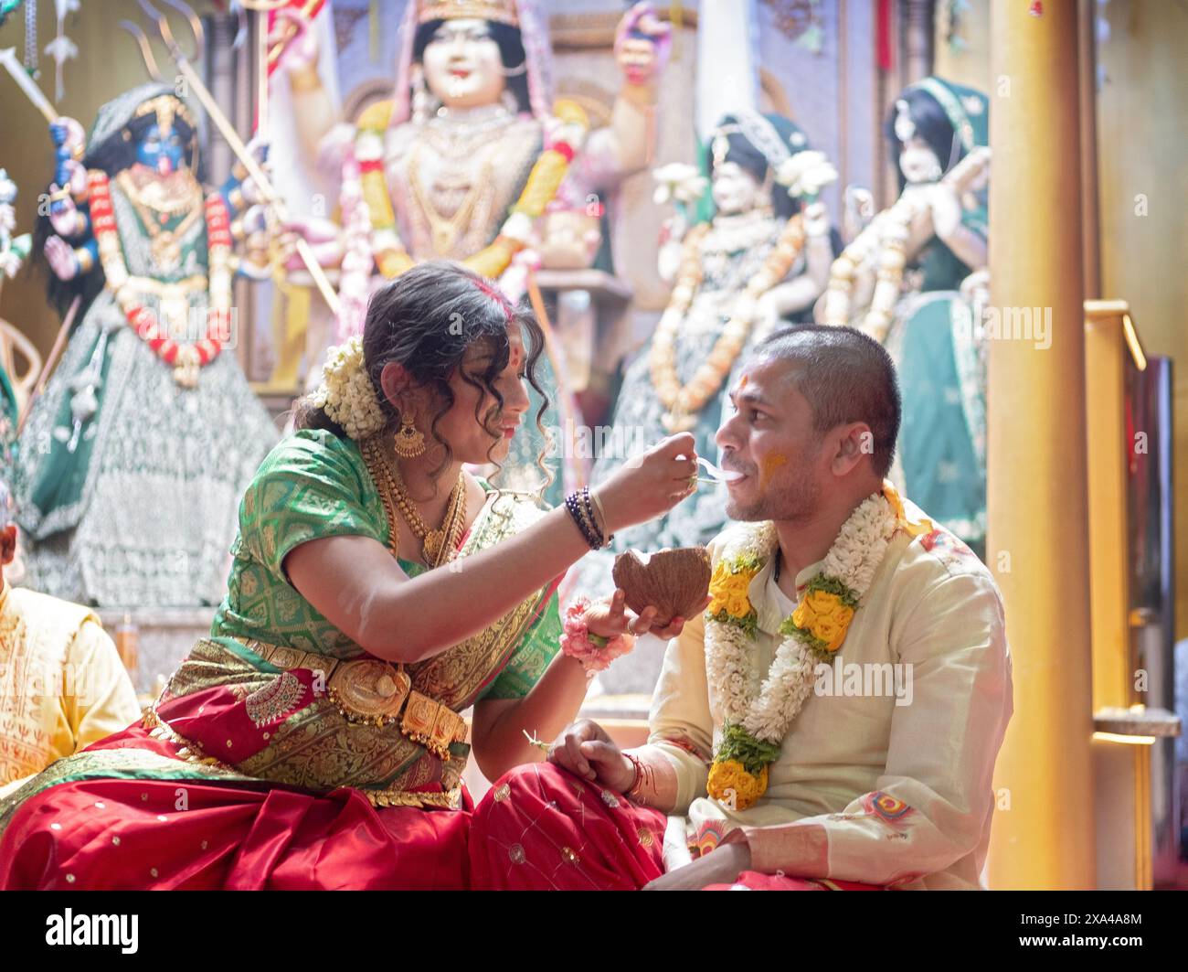 During a Valaikappu service a pregnant woman feeds her husband from a ...