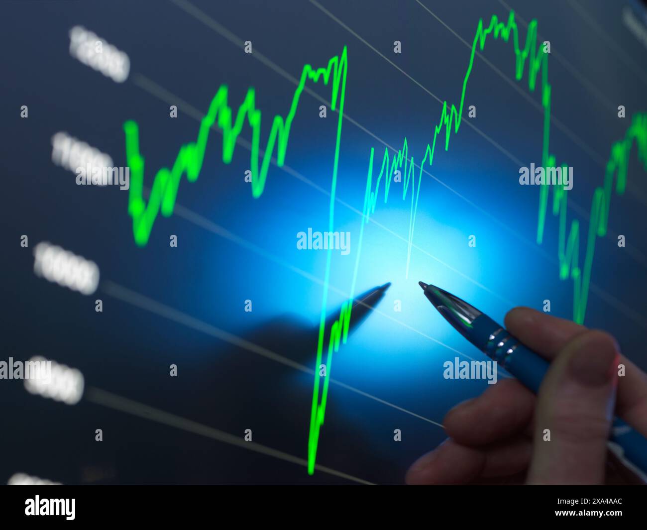 A person's hand holds a pen, pointing at a bright screen displaying a ...