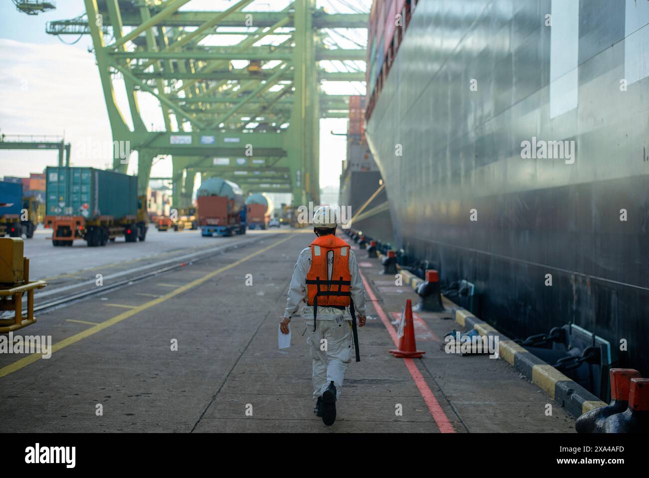 A worker in orange high-visibility gear and a hard hat walks toward a ...