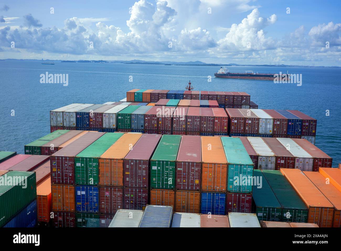 A cargo ship stacked high with colorful shipping containers is sailing ...