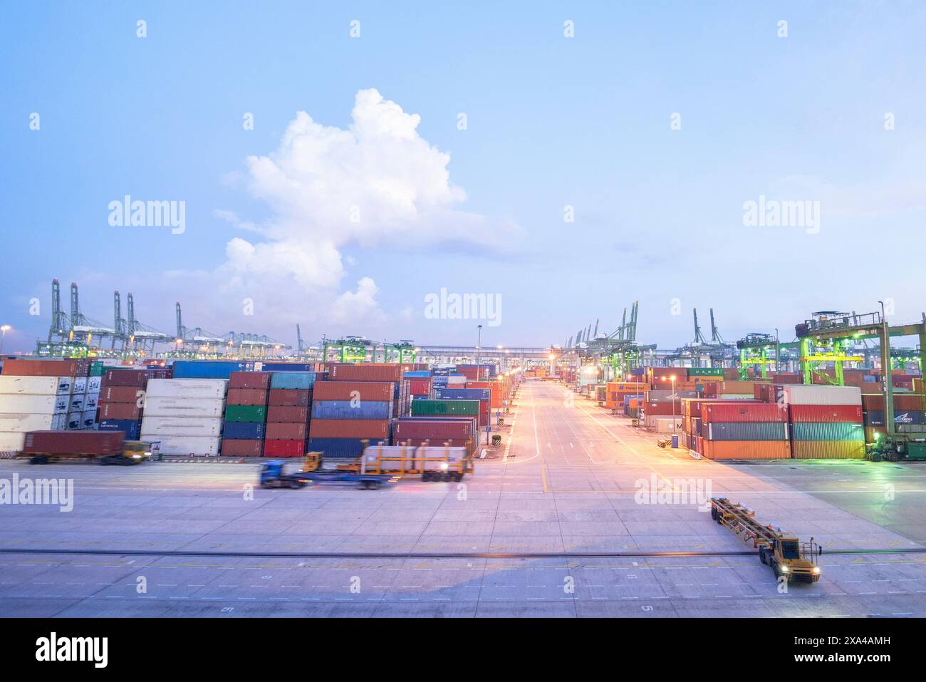 A busy container terminal during twilight with stacks of multicolored ...