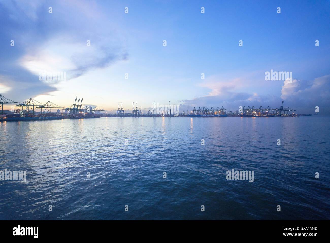Dawn breaks over a busy port with rows of cranes lining the docks, and ...