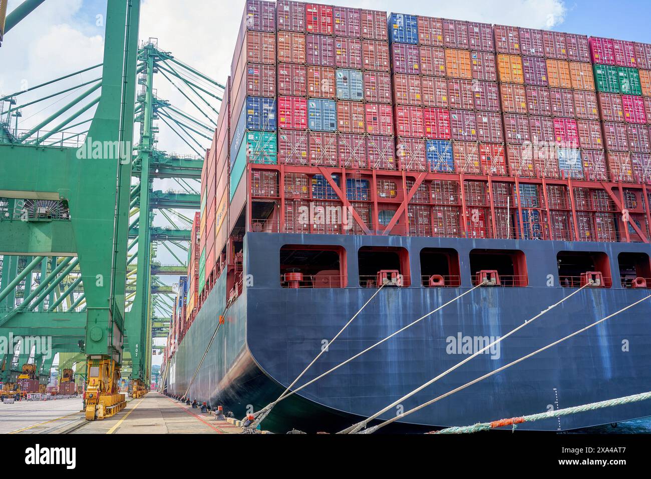 A large cargo ship loaded with colorful containers is docked at a port ...