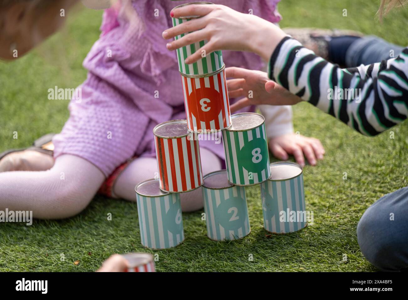 Children playing with a colorful stack of cans designed with numbers ...