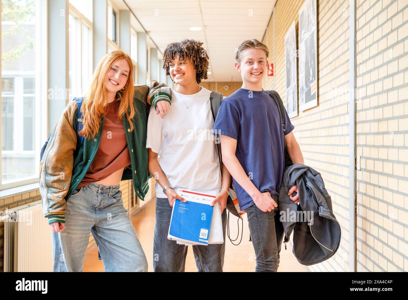 Three students are smiling posing school hallway hi-res stock ...