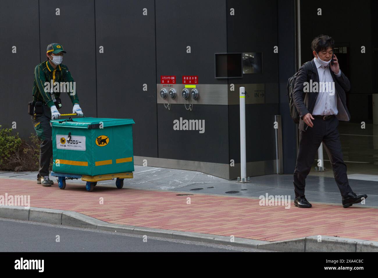 A Yamato Delivery Company worker pushes a cart for deliveries along a ...