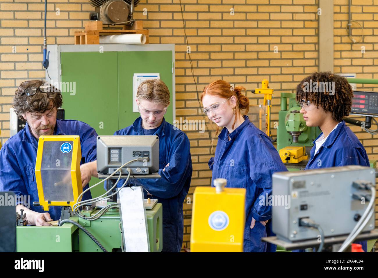 Four people are attentively observing equipment in an industrial or ...