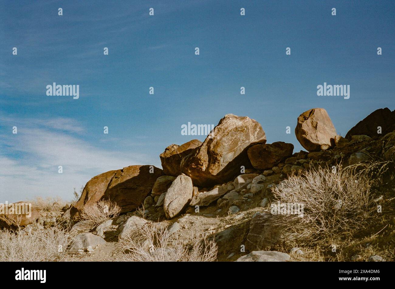 A rugged desert landscape featuring large boulders under a clear blue ...