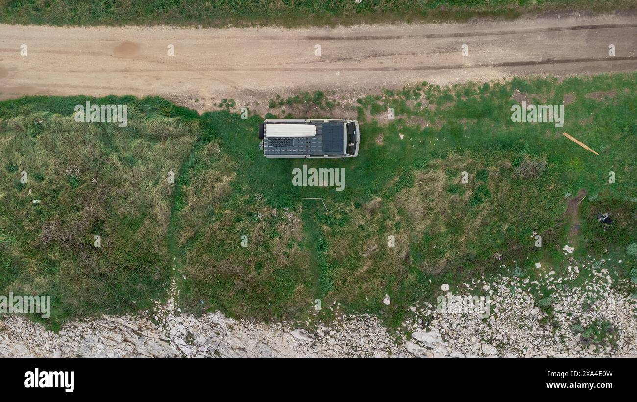Above view of an adventure camper parked next to a gravel road. Solar ...