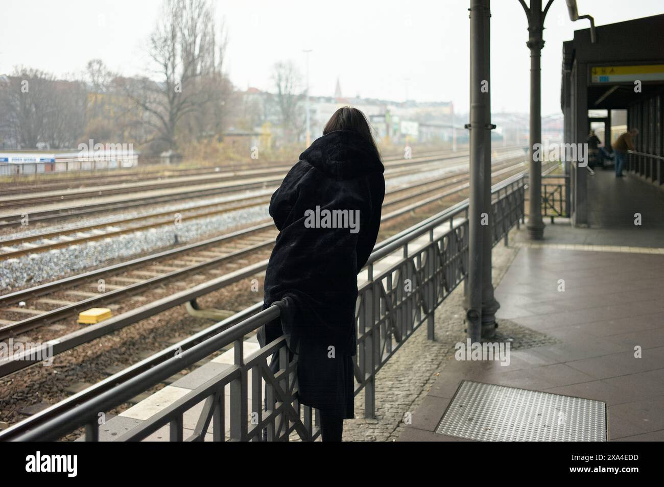 Person stands leaning railing train station platform hi-res stock ...