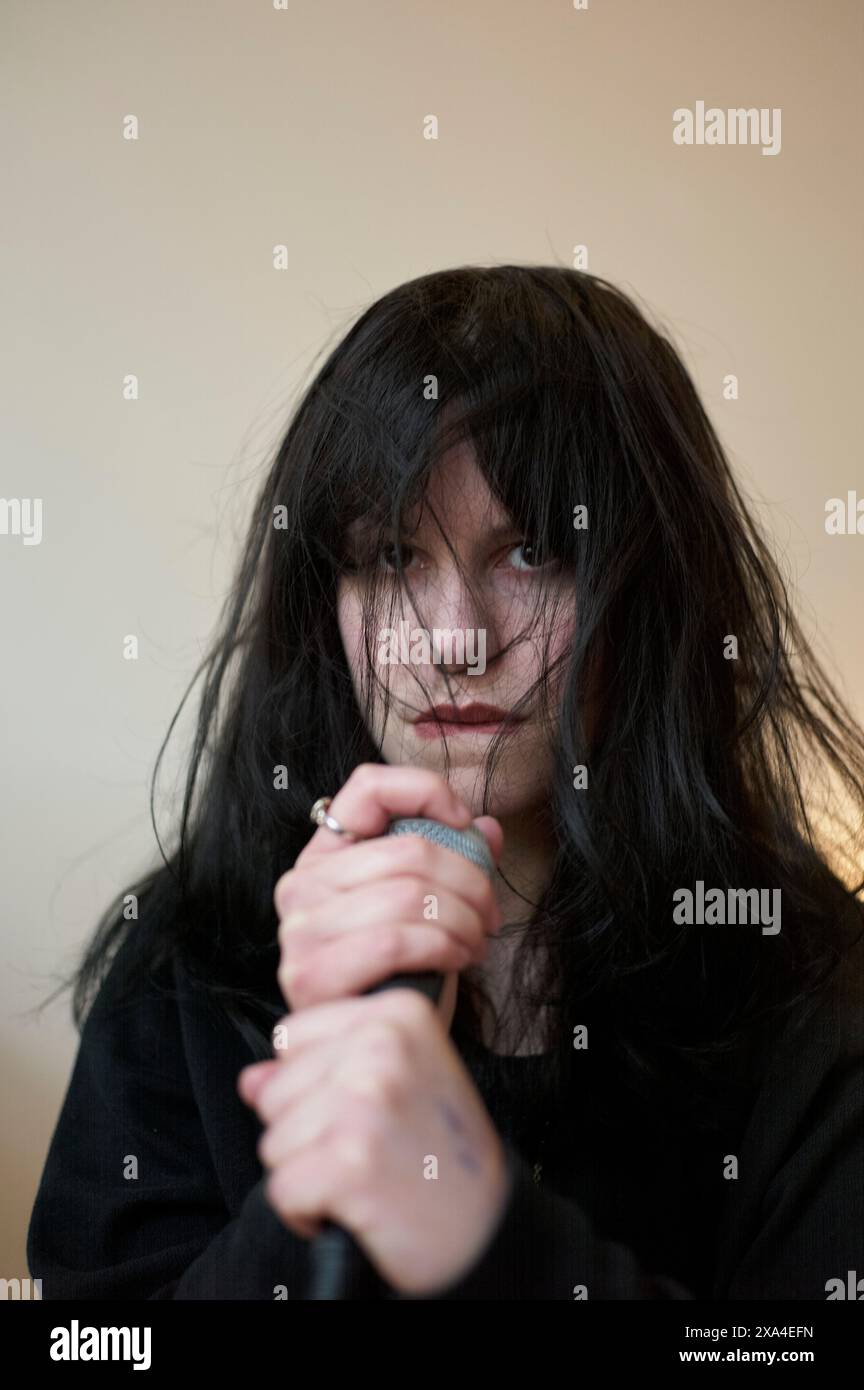 A person with shoulder-length black hair is singing into a microphone ...