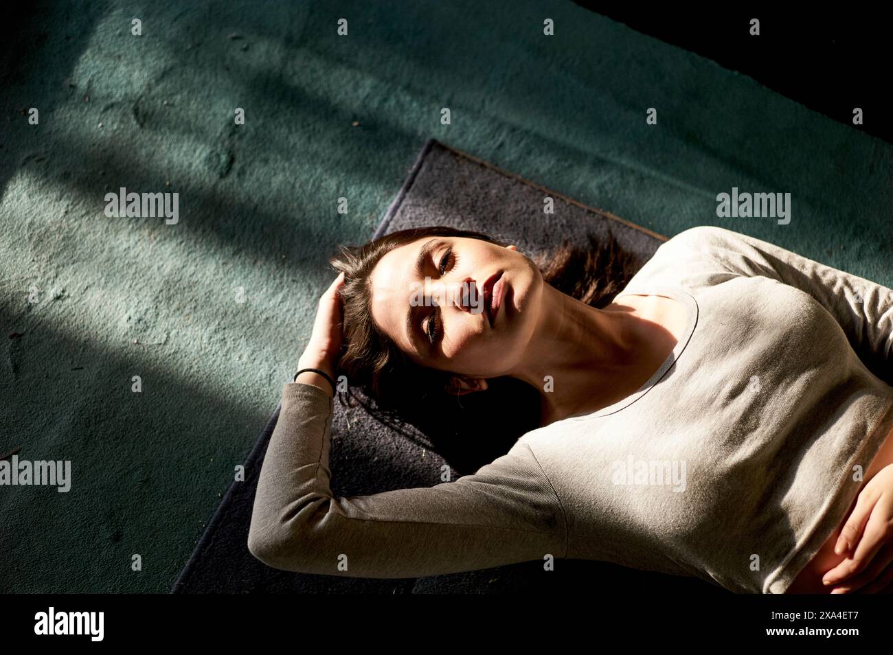 A woman is lying down on a dark surface with her head resting on her ...
