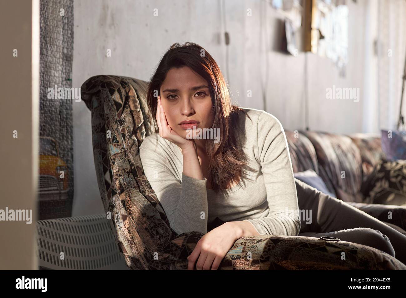 Woman rests head hand sitting couch covered patterned blanket hi-res ...