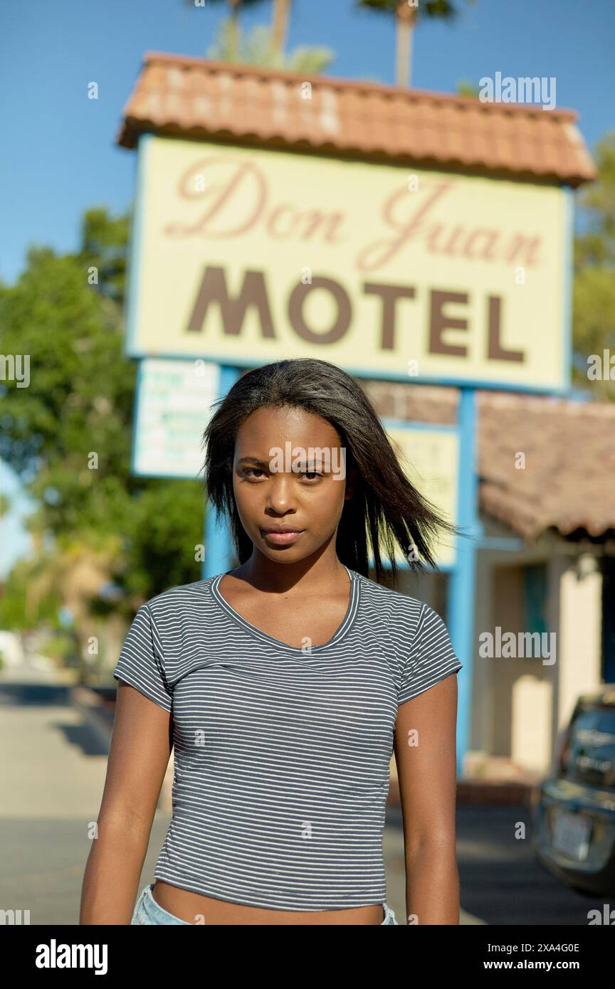 A young woman is standing in front of the Don Juan Motel sign during the daytime Stock Photo - Alamy