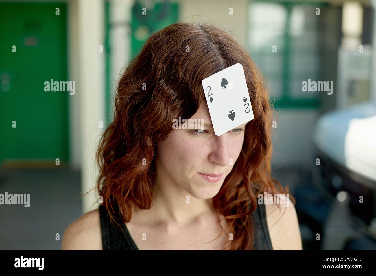 A woman with red hair is seen with a playing card stuck to her forehead ...