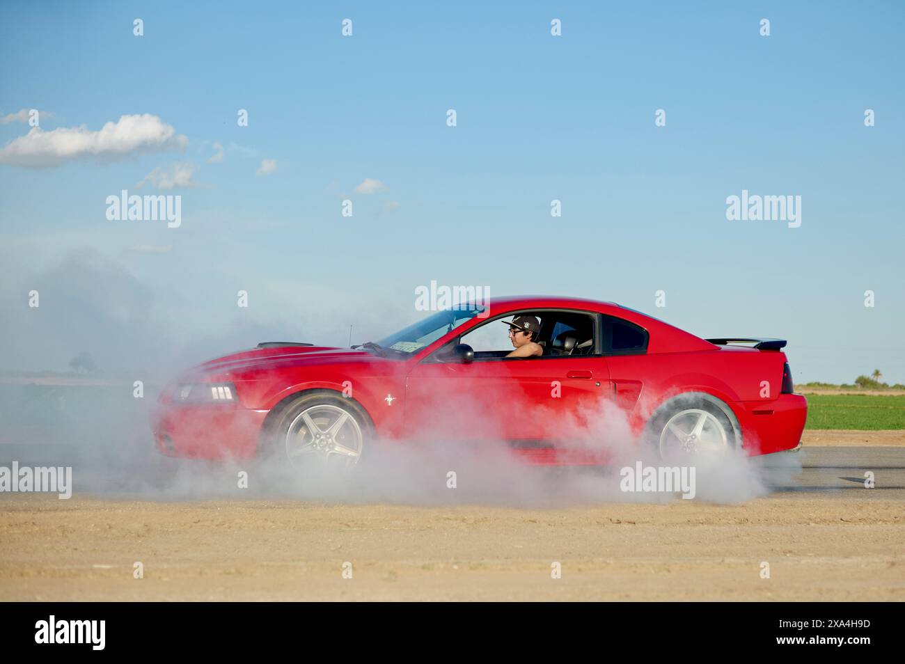 A red sports car is performing a burnout, with white tire smoke ...