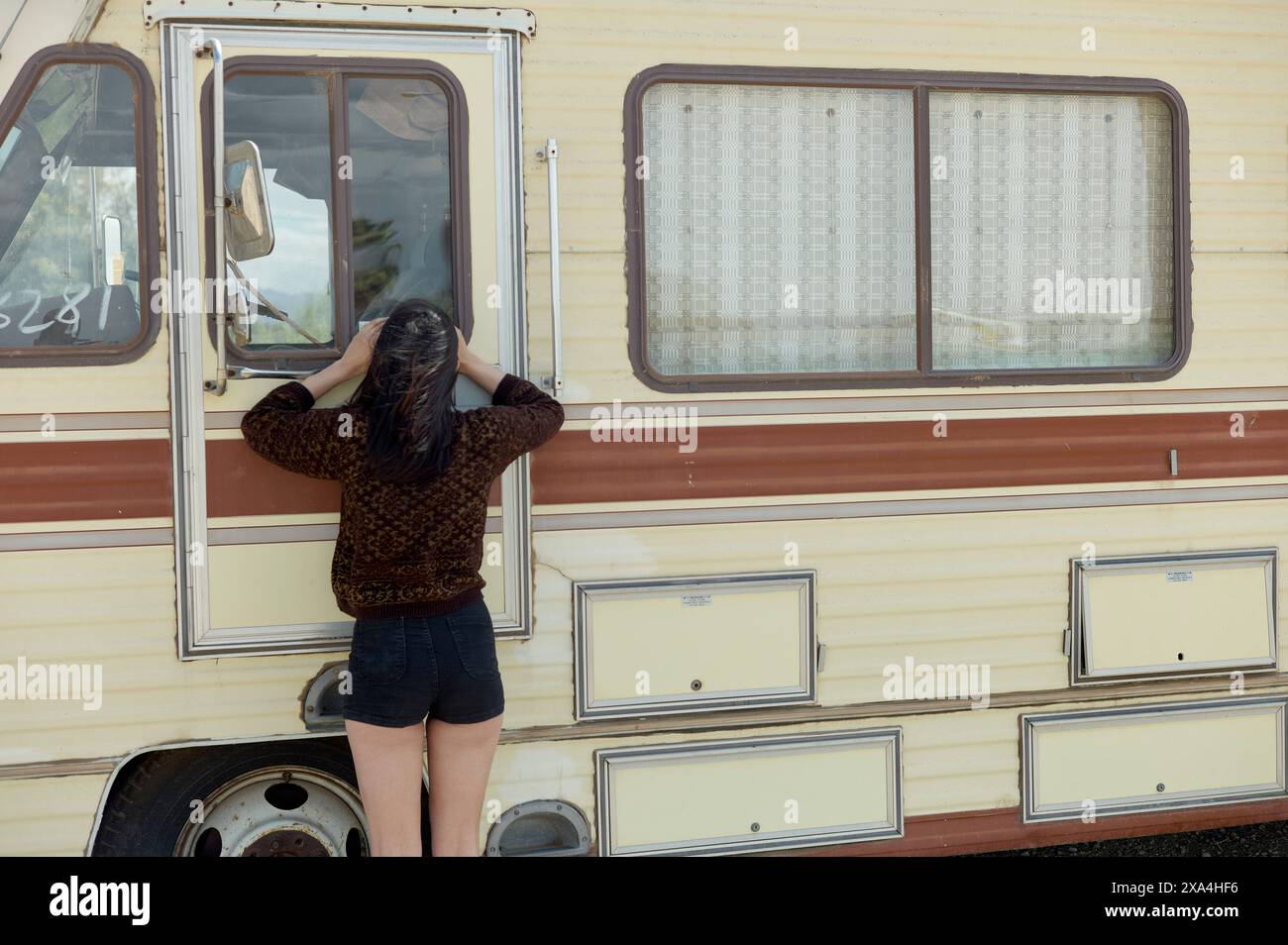A person standing by an old RV, peering through a window with their ...