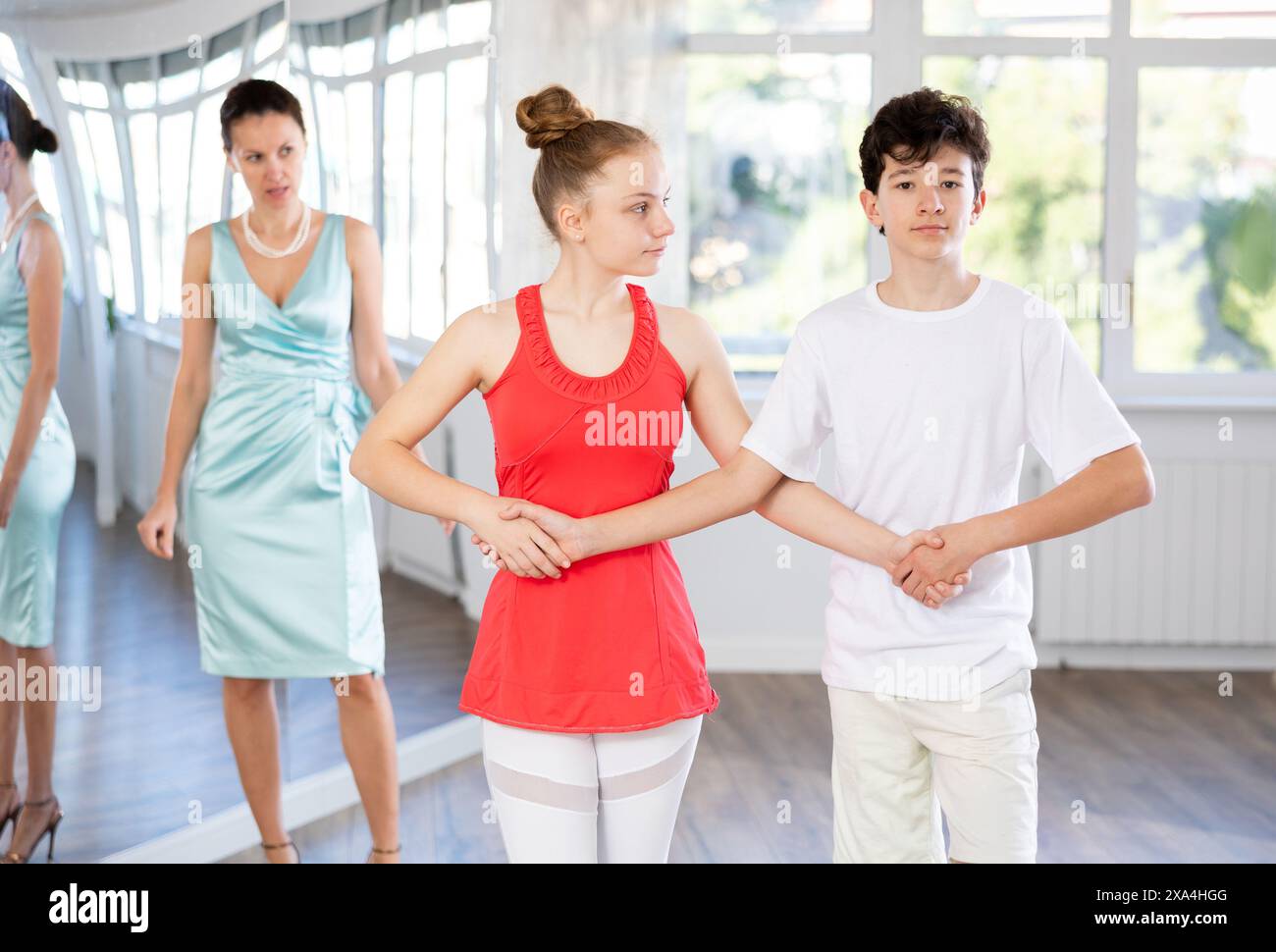 Smiling teenage boy and girl practicing cheerful polka at dance lesson ...