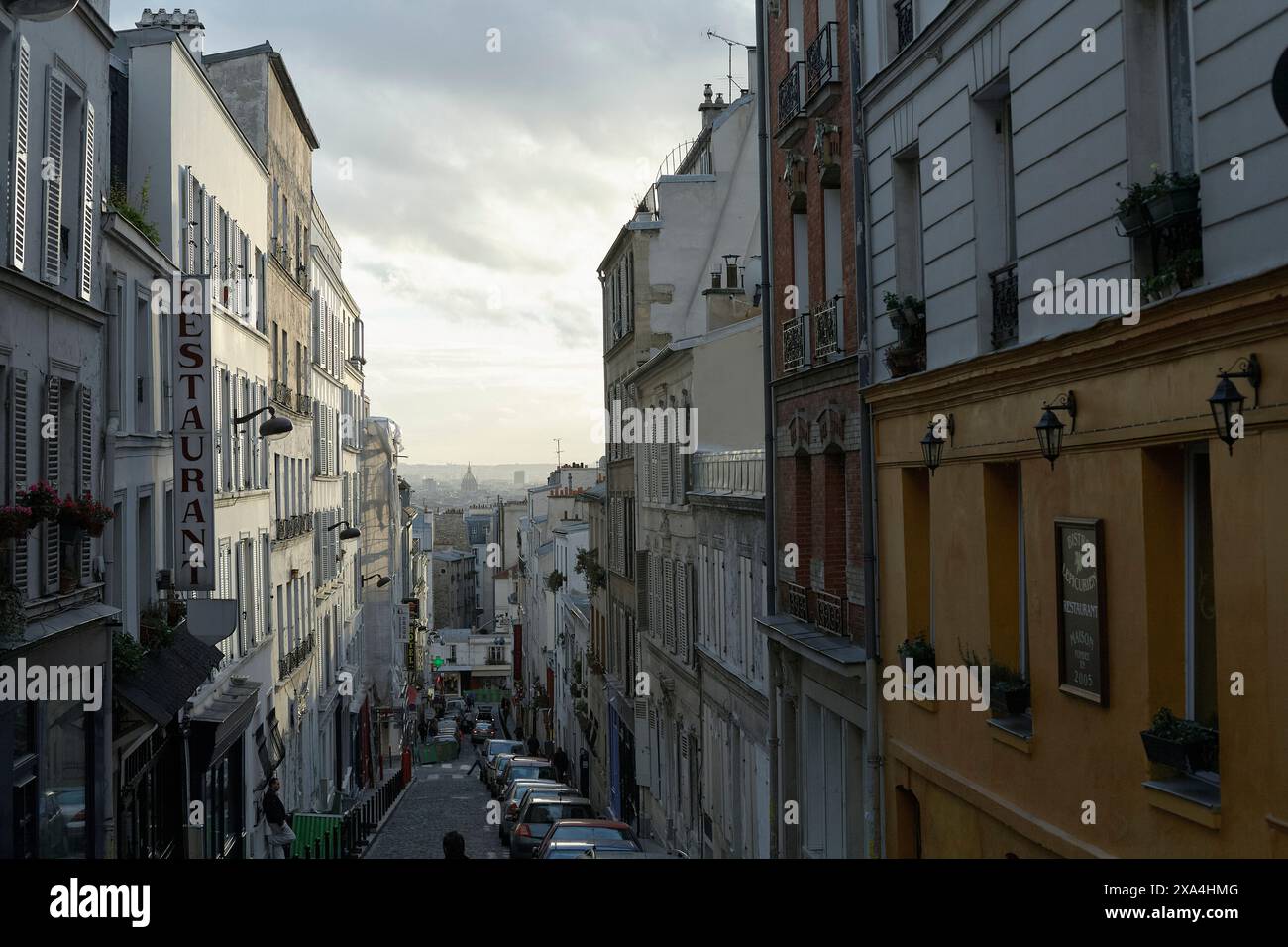 A view of a narrow European street lined with traditional buildings ...