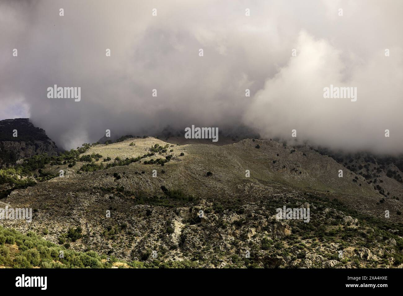 A mountain landscape under a dramatic, cloudy sky with the clouds ...