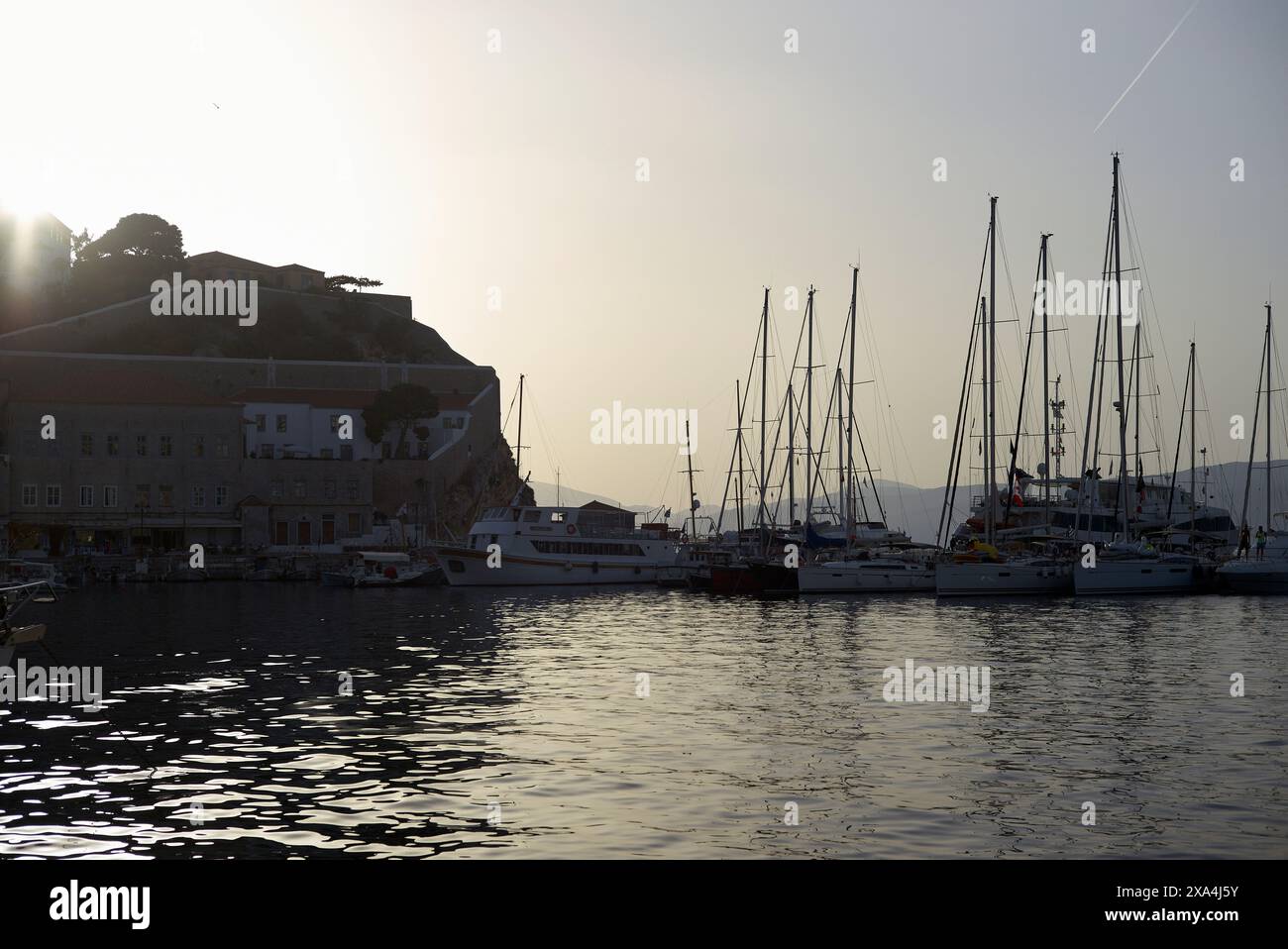 Sunset over calm harbor silhouettes anchored sailboats yachts hill ...