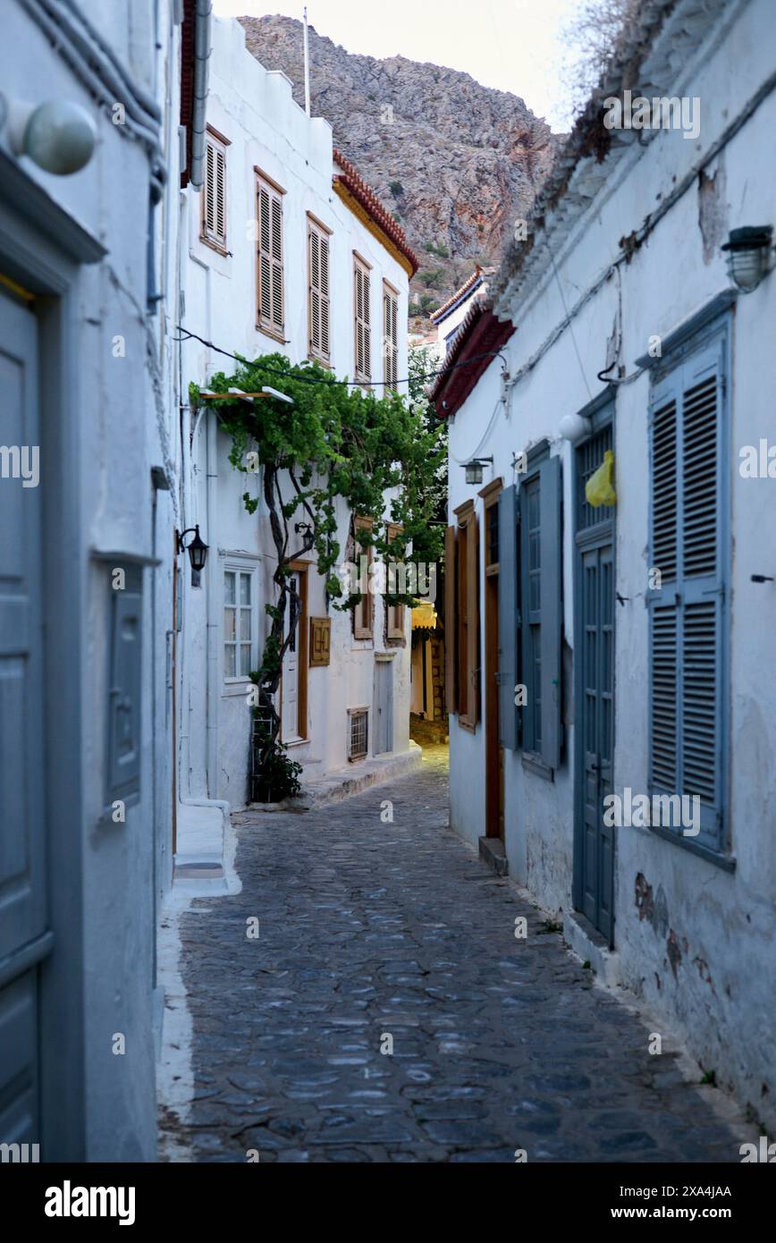 A narrow cobblestone street flanked by traditional white houses with ...