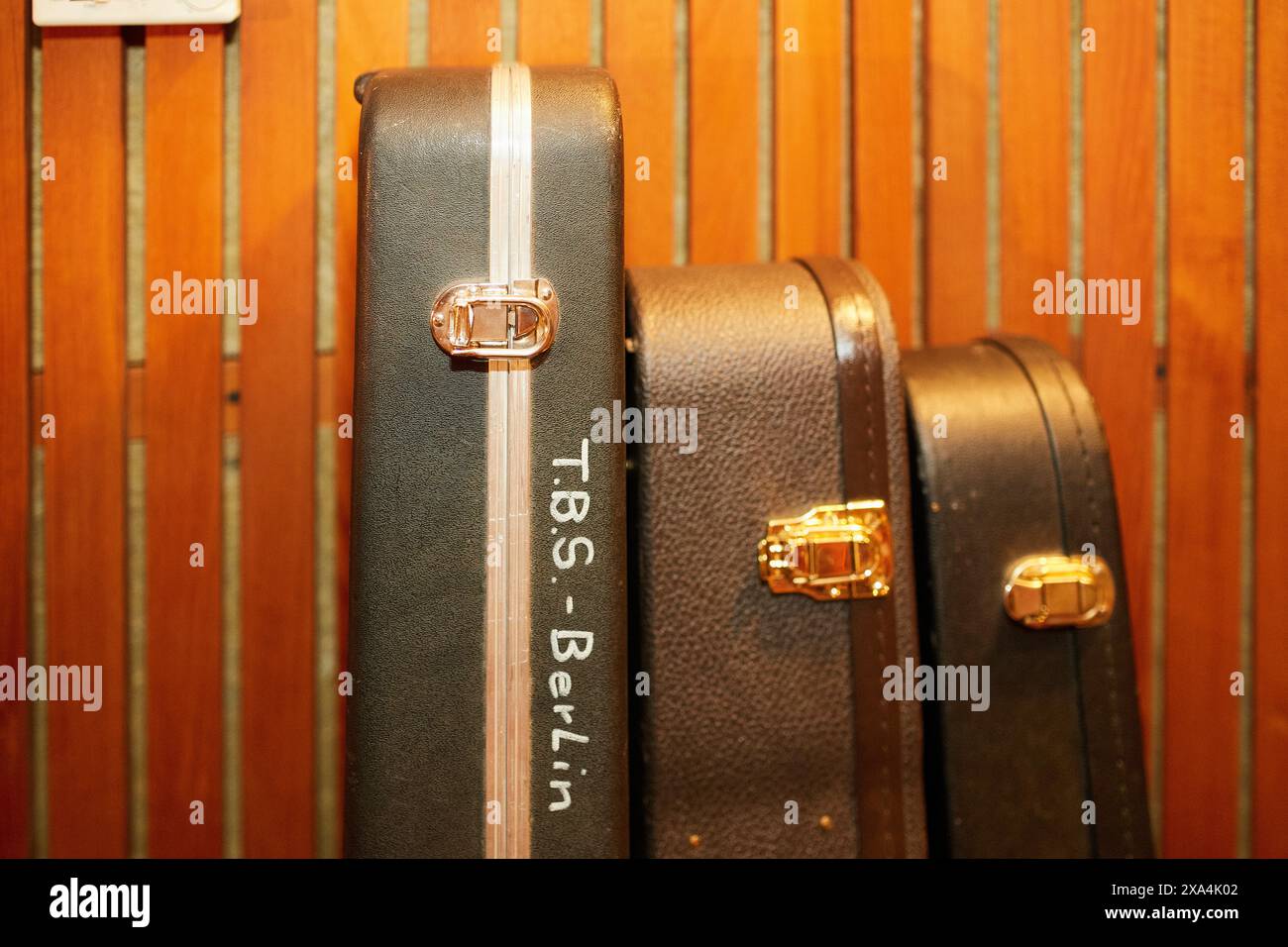 Two upright guitar cases are standing against a wooden-slatted ...